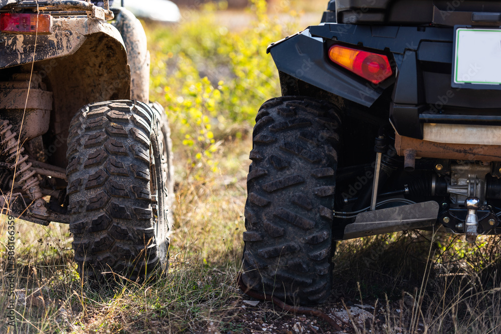 Close-up tail view of ATV quad bike on dirt country road. Dirty wheel ...