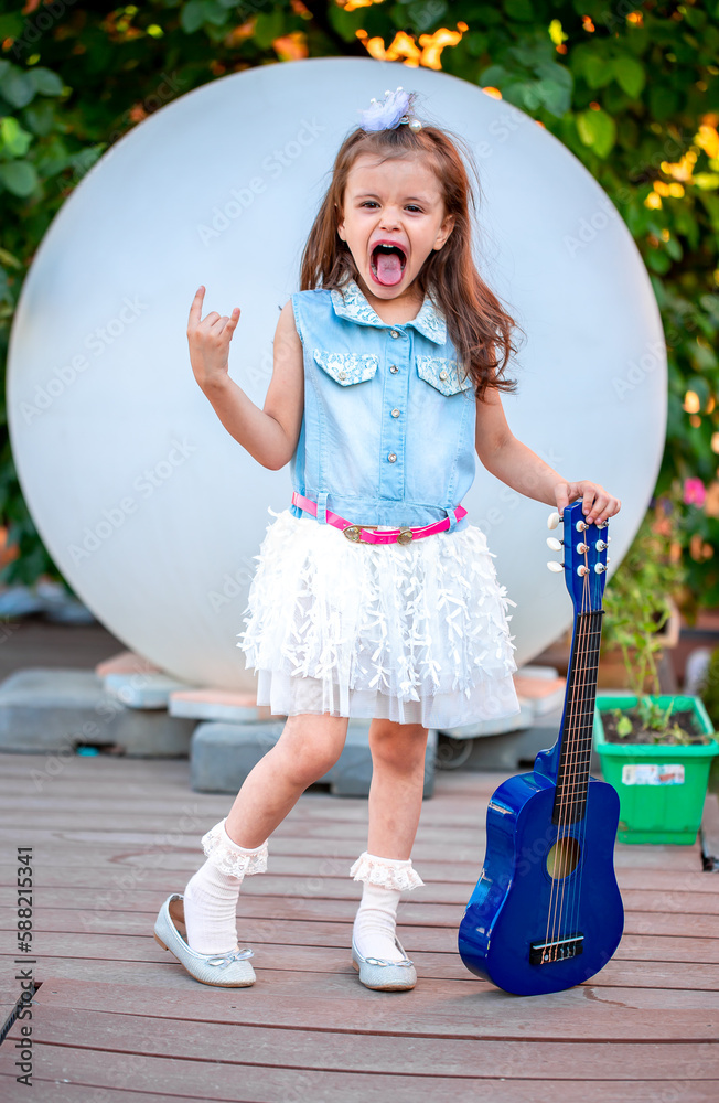 A little girl of European appearance plays the guitar on an impromptu ...