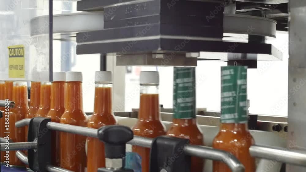 Hot sauce bottles being labelled at industrial factory-Chilli pepper ...