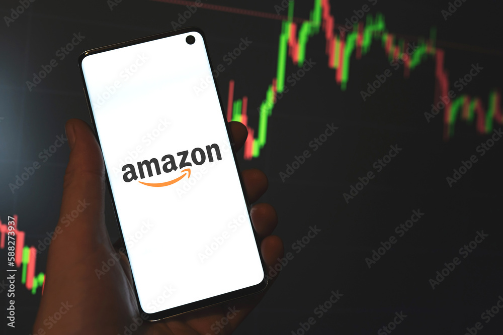 Amazon Inc. logo displayed on phone screen in hand, stock chart, line ...