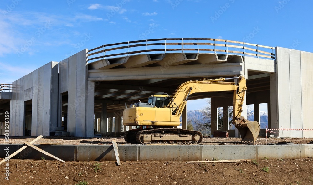 Side view of excavator in front of new commercial building under ...
