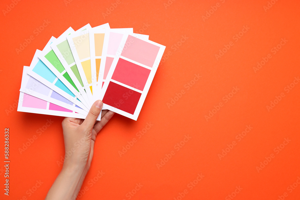 Female hand holding color palettes on orange background Stock Photo ...