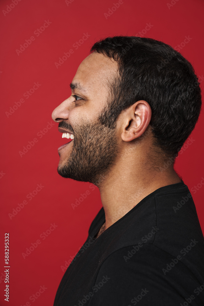 Profile of indian man smiling isolated over red studio background ...