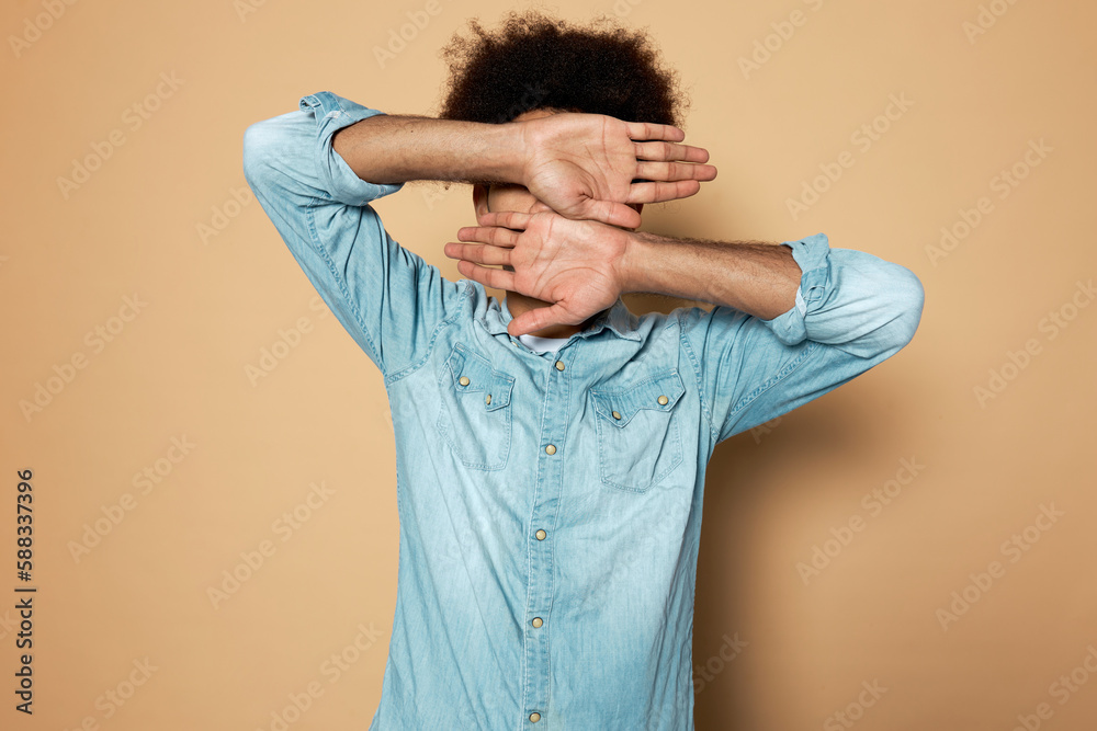 Man playing seek and hide game standing against brown studio background ...