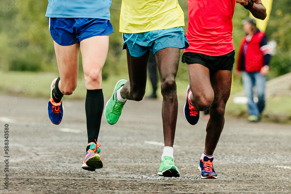 two african and european runners running marathon, front view legs ...