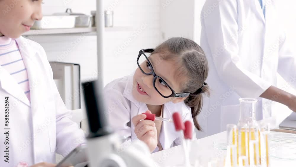 Cute little girl wearing lab coat learning chemistry in school ...