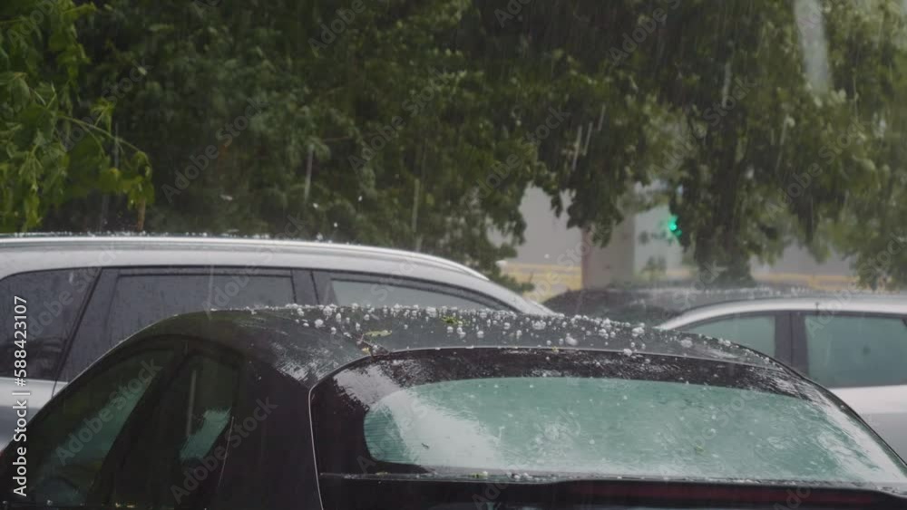 Hail during heavy rain falls on roof and windshield of black car ...