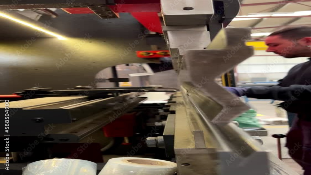 vertical 4k video of side view of a metal bending machine of a worker ...