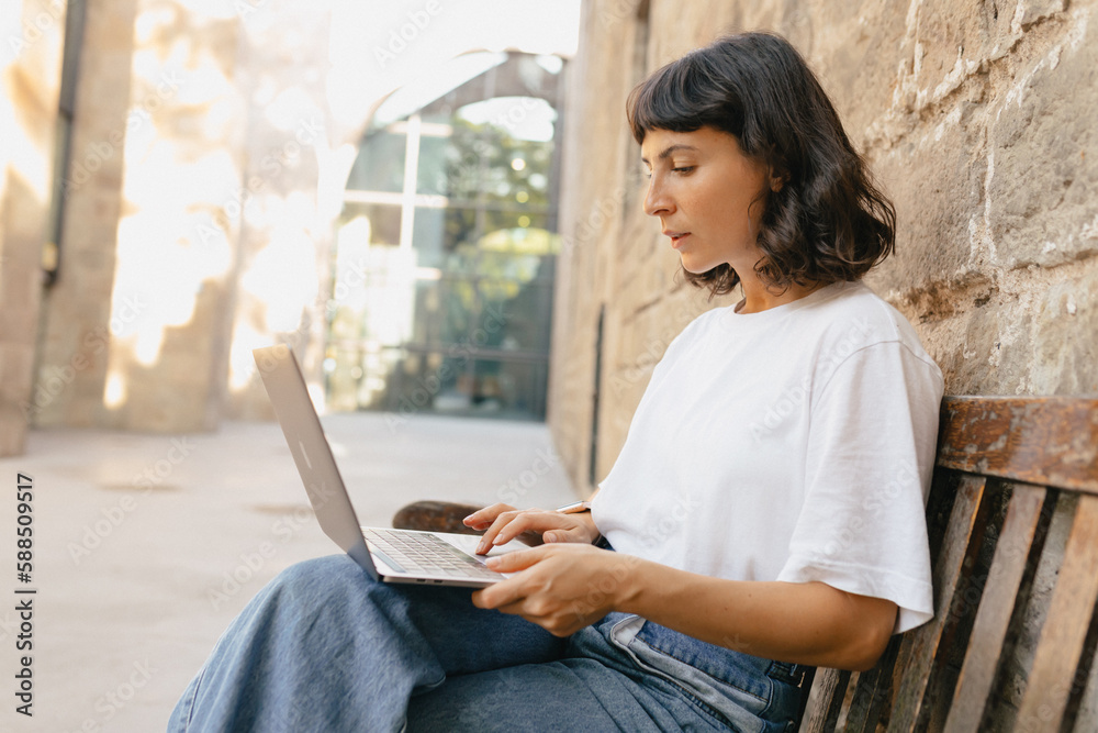 Cute stylish young lady sitting with laptop outdoors and smiling ...