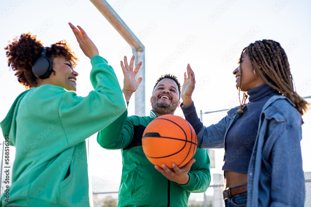 A group of happy and diverse friends gather on a basketball court. The ...