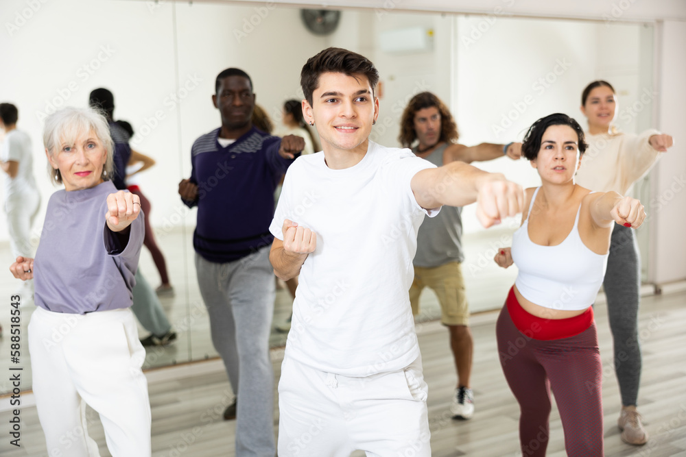 Smiling young guy standing in attacking stance, practicing movements of ...