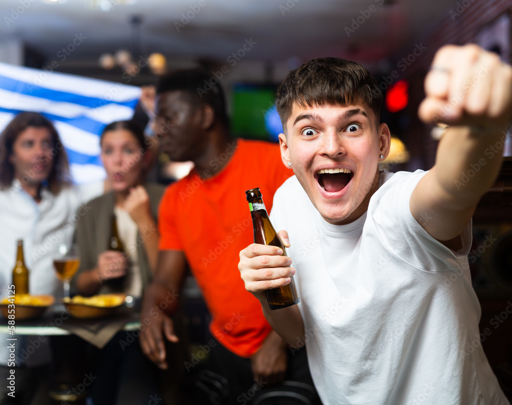 Excited young guy watching football match in sports bar, emotionally ...