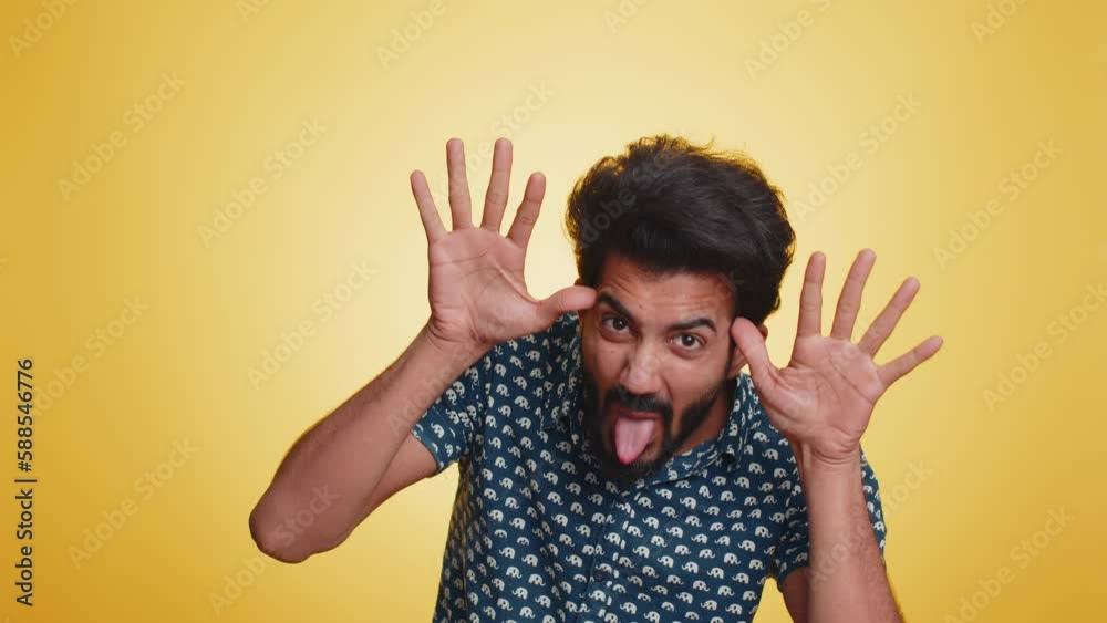 Young indian man showing tongue making childish faces at camera ...
