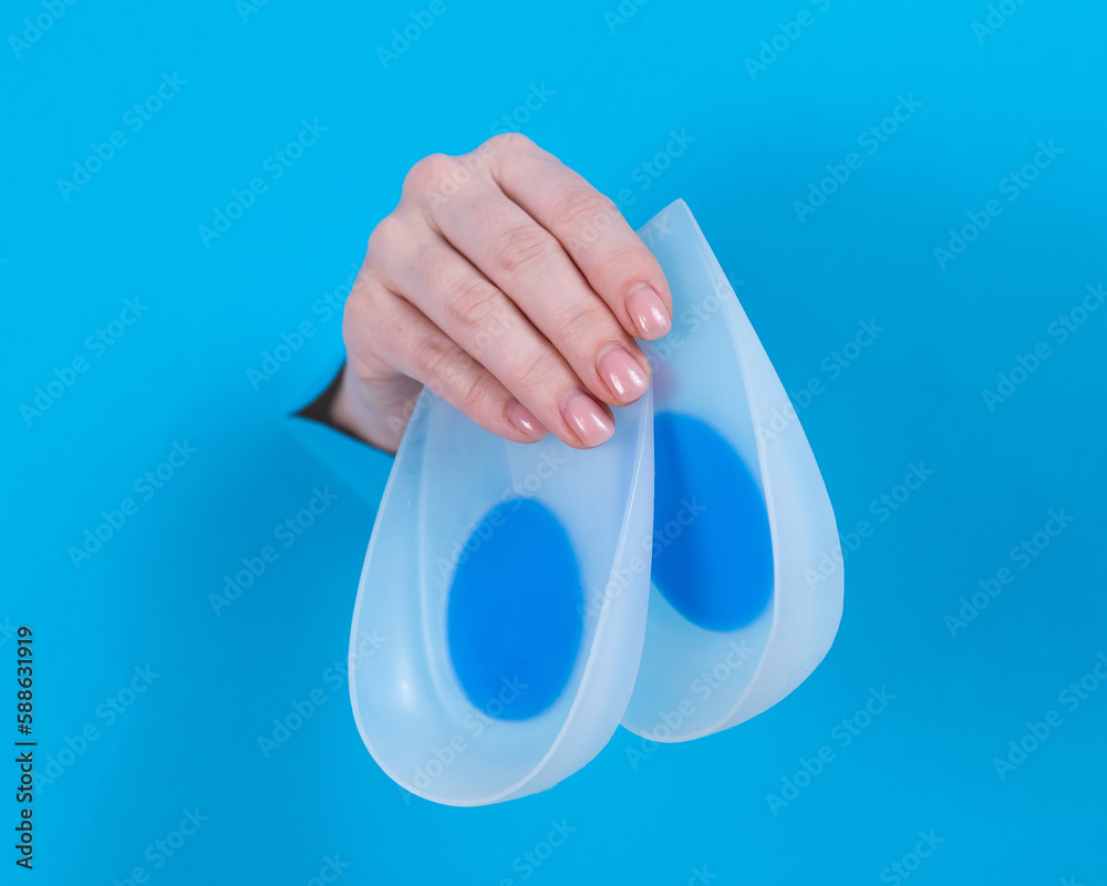 Woman holding orthopedic silicone heel pads. A woman's hand sticks out ...