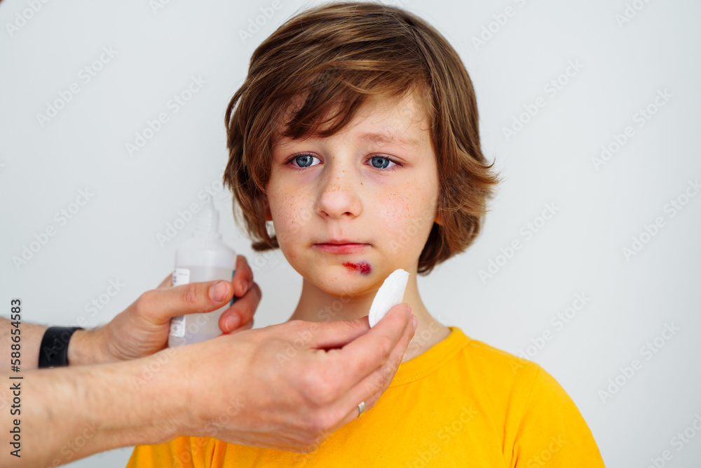 Dad doctor father treats bruised wound on his son school boy kid face ...