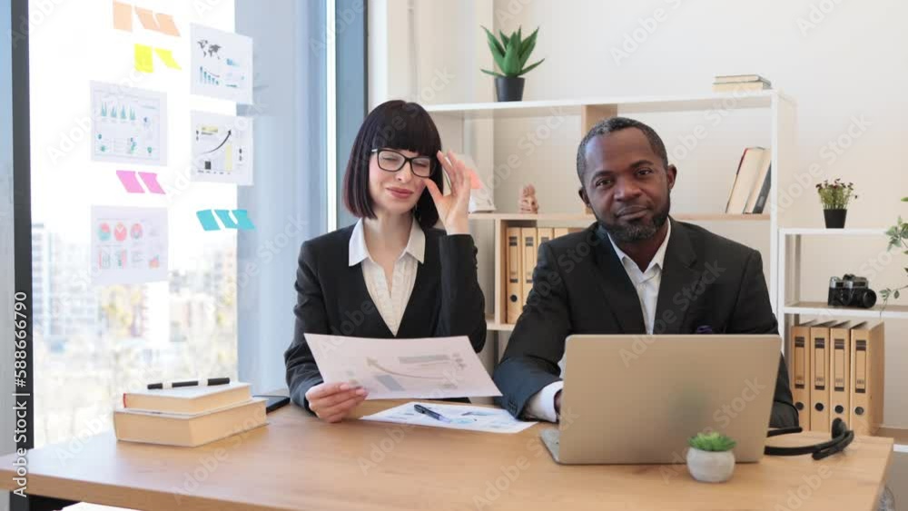 Multicultural white-collar male worker with laptop and his female ...