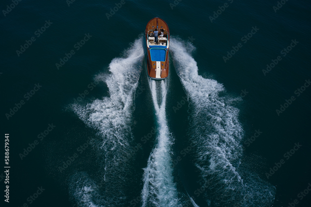 Large motor boat with people moving on the water, making a white trail ...