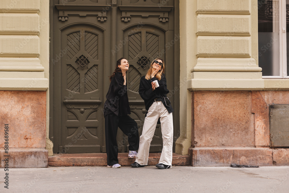 Two happy smiling women standing near door outdoor on the street and ...