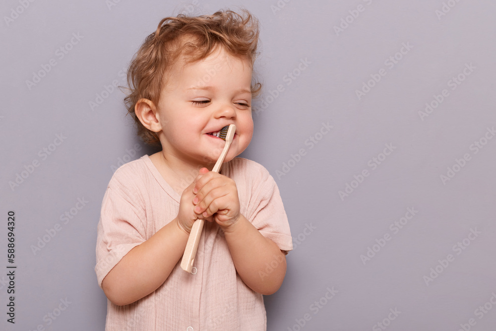 Horizontal shot of happy kid girl brushing teeth, holding toothbrush in ...