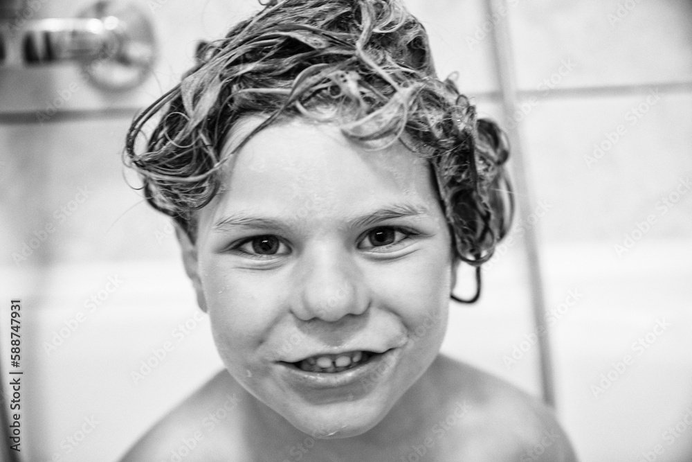Cute child with shampoo foam and bubbles on hair taking bath. Portrait ...