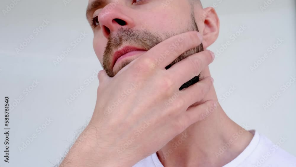 close-up part of the face, bearded young man 30 years old touches his ...