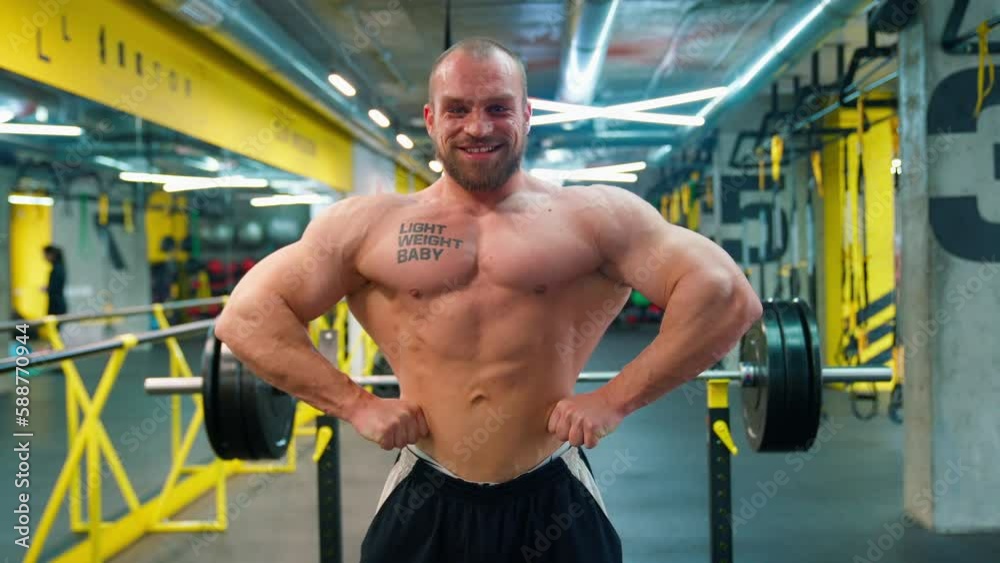 Wideo Stock: Bald bodybuilder exercising in the gym. Raises the barbell ...