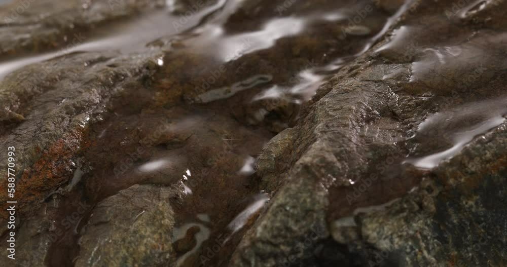 water flows over grey stone. stone texture close-up. rought mountain ...