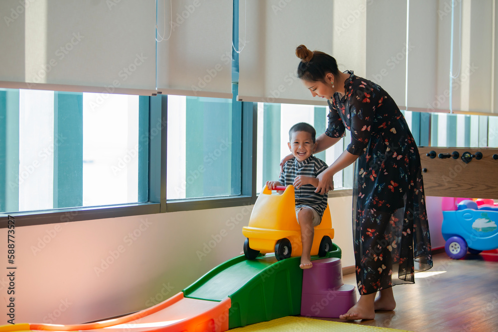 Cute Asian woman and kid playing educational toys together in living ...