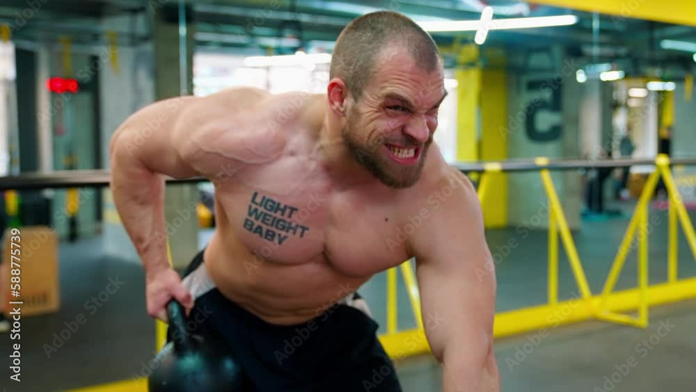Bald bodybuilder exercising in the gym. Raises the barbell, dumbbells ...