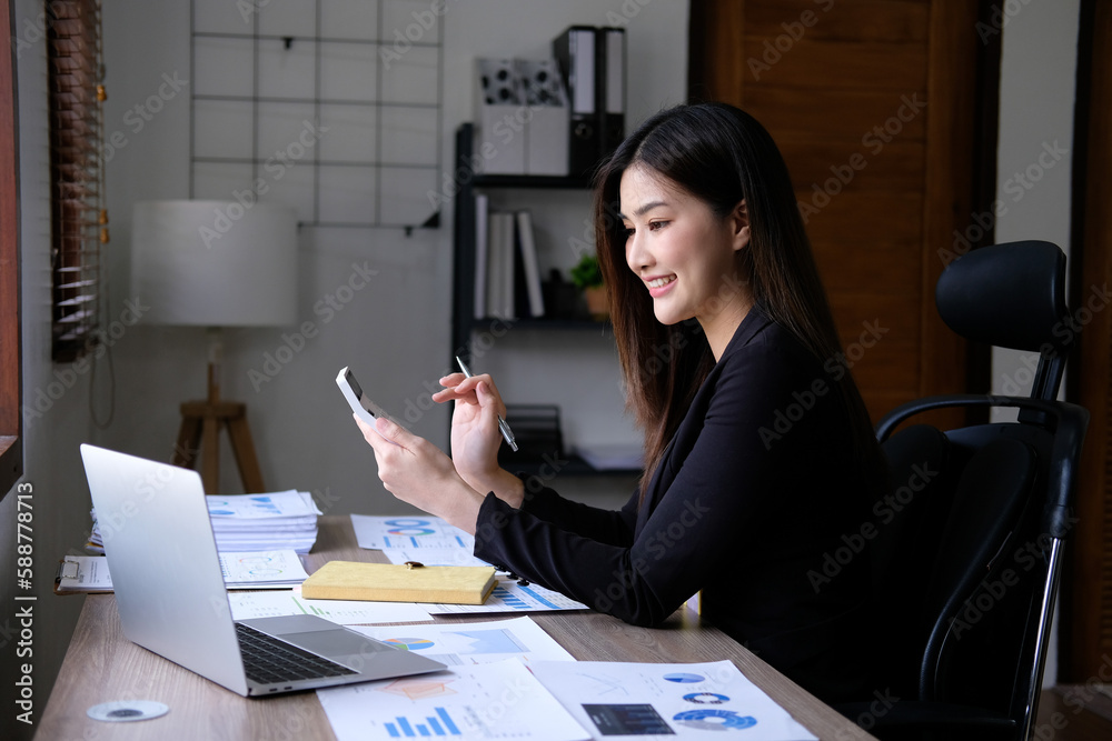Female attractive asian banker accountant wearing red formal suit calculate the cash bill of ...