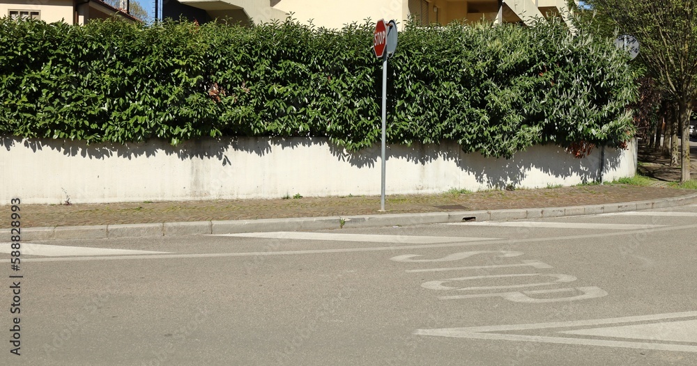 Stop sign and stop word painted on asphalt. On behind a white fence ...