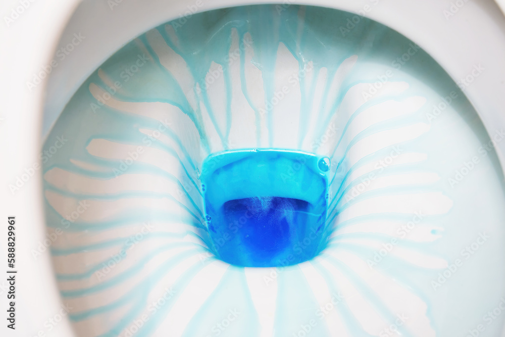 Closeup view of toilet bowl during cleaning with blue detergent ...