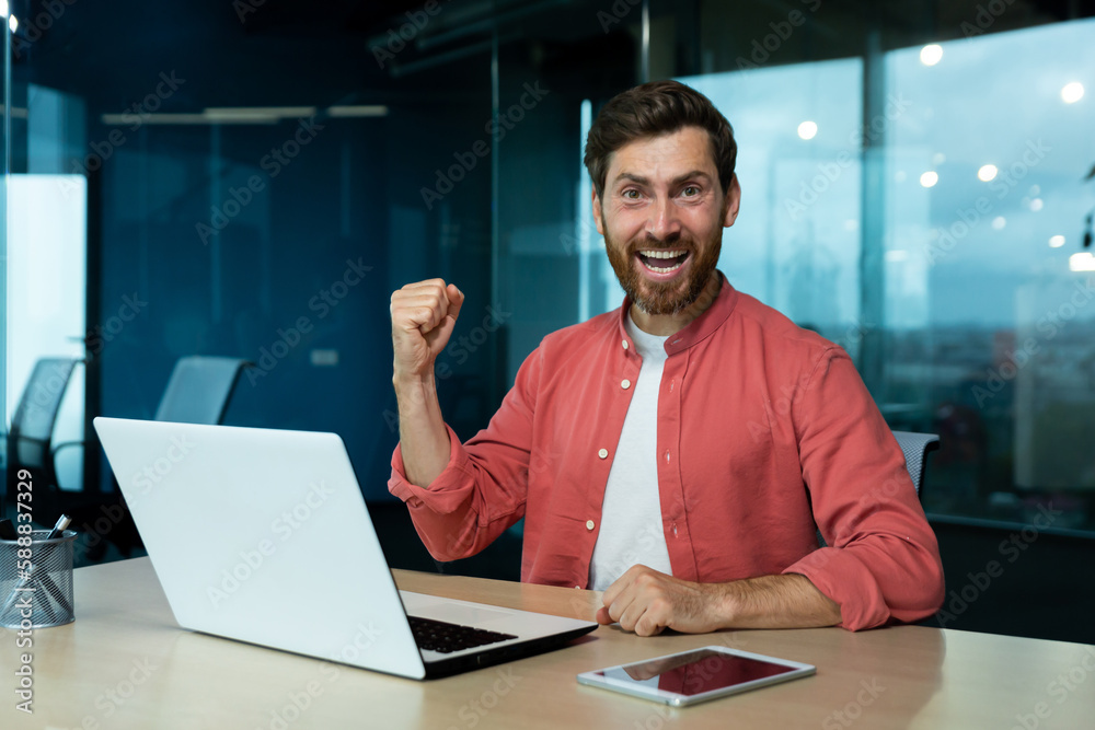 Happy young student sitting in office, campus in front of .aptop ...