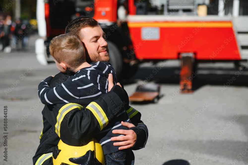 Portrait of rescued little boy with firefighter man standing near fire ...