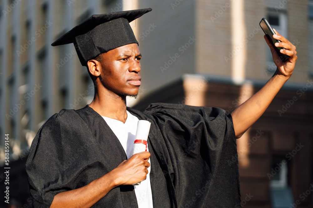 Serious african american graduate from university taking photo with ...