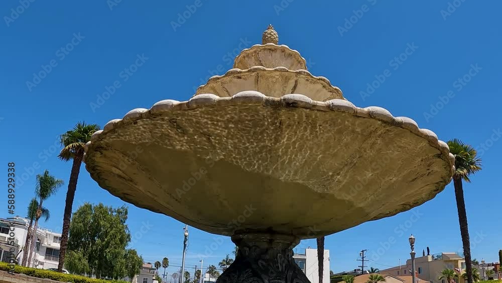 footage of a white three layer water fountain with the water reflecting ...