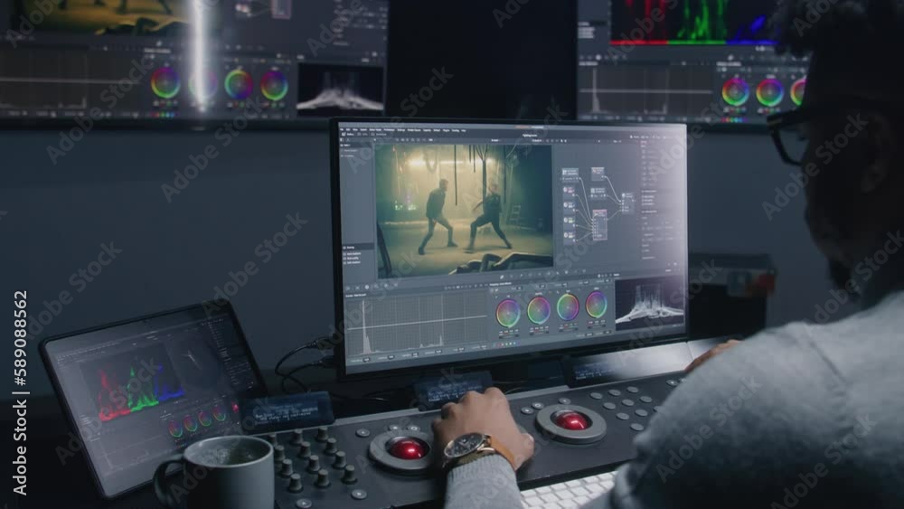 African American film editor does color grading on control surface in ...