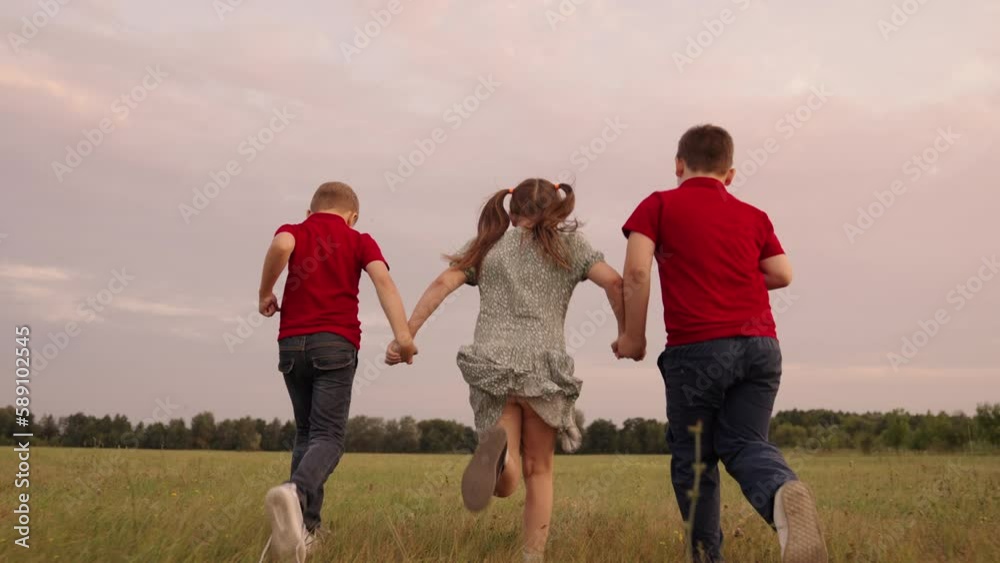 child run on green grass holding hands. friendly team of children ...