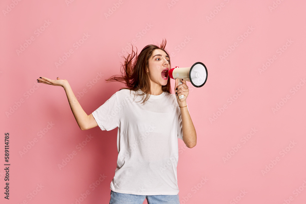 Portrait of young girl in white t-shirt shouting in megaphone against ...