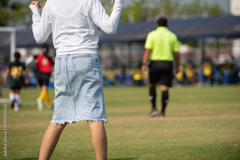 Mother standing and watching her son playing football in a school ...