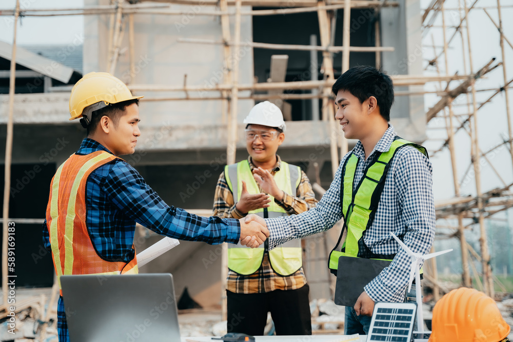 Construction workers, architects and engineers shake hands while ...