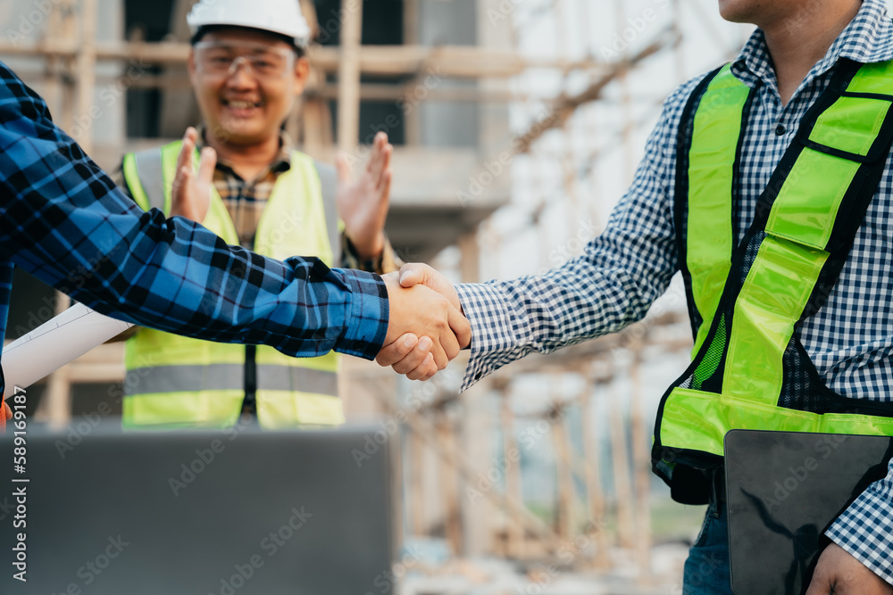 Construction workers, architects and engineers shake hands while ...
