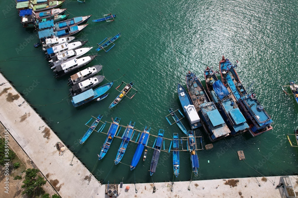 blue and white fishing boat anchored in a harbor. aerial photography of ...