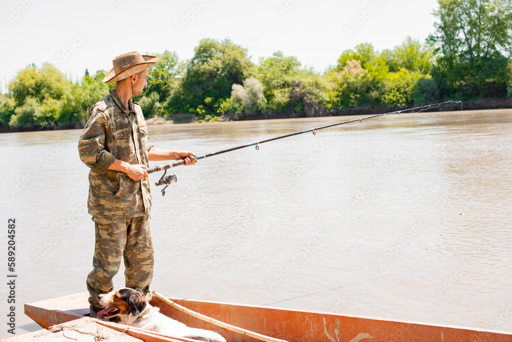 Thoughtful man in camo apparel standing at stern of boat, fishing in ...