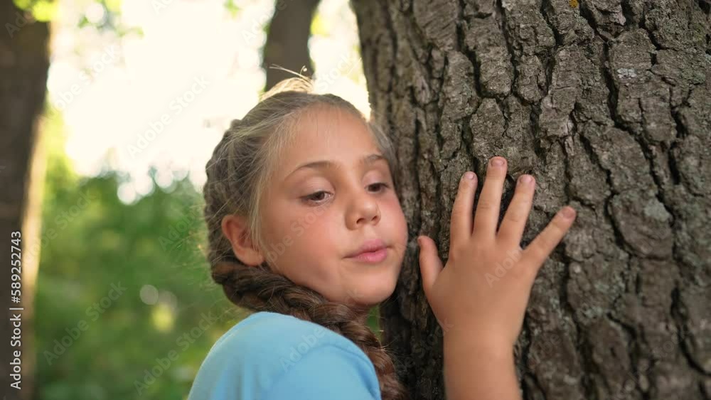 a small child ecologist hugs the trunk of a tree bark in a forest park ...