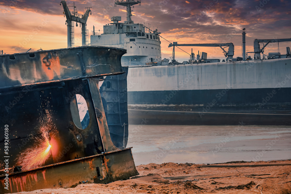 Shipbreaking of a large oil tanker in the harbor, labour cutting the ...