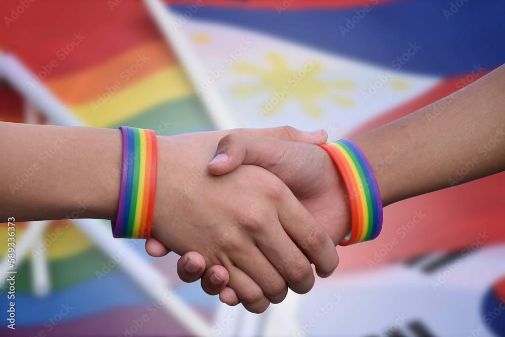 Closeup view of handshaking of LGBT people with blurred rainbow ...