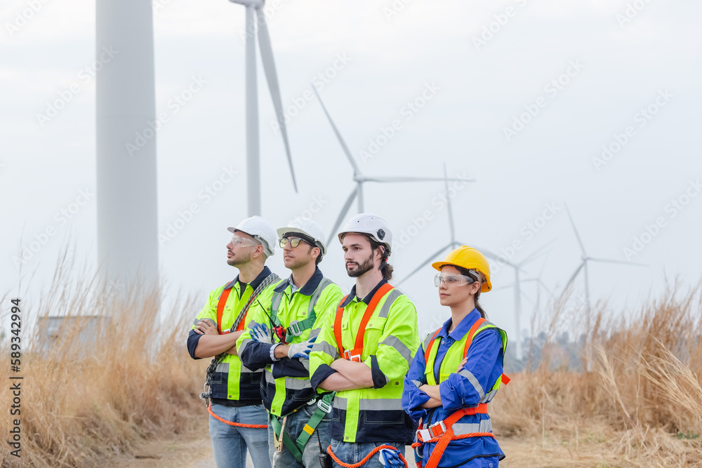 Teamwork engineer wearing safety uniform standing crossed arms at wind turbine field renewable ...