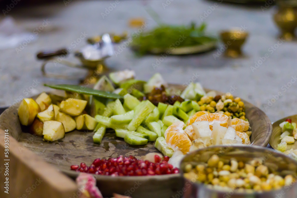 Various fruits and vegetables are kept together in brass plates for ...