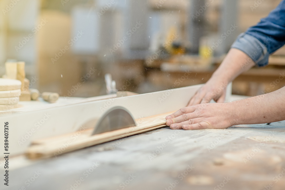 Carpenter cutting a piece of wood at workshop, using a circular saw ...